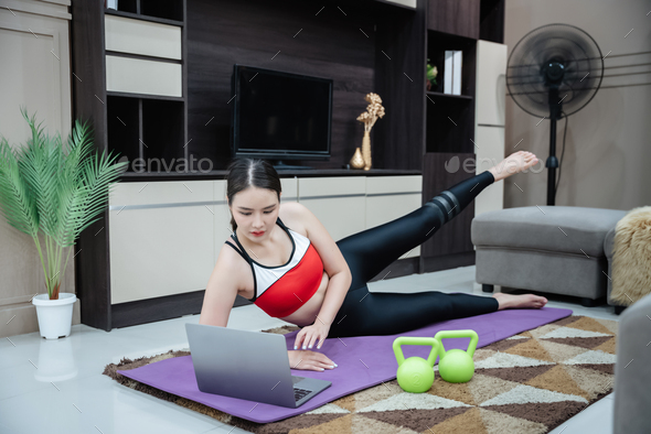 A young woman exercises with simple equipment and learns new exercises ...