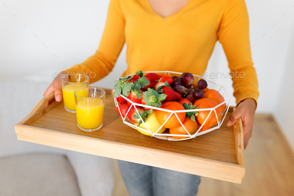 Black Lady Holding Tray With Fruits And Juice Indoor, Cropped Stock Photo by Prostock-studio