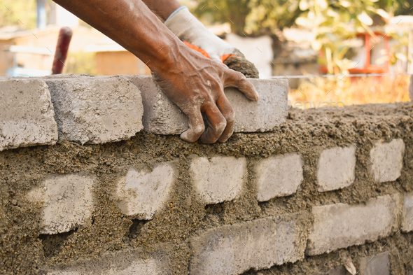 Closeup of a man building a wall with bricks, outdoors during daylight ...