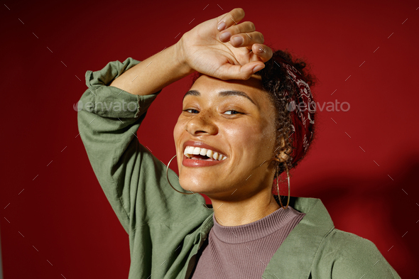 Woman posing with touching forehead by hand and looks camera with smile ...
