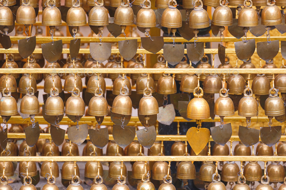 Group of many small brass praying bells hanging on steel lines at Thai ...