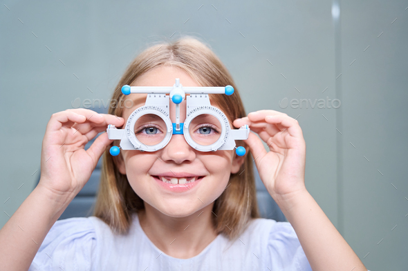 Cheerful little girl undergoing eye exam with refraction test Stock ...
