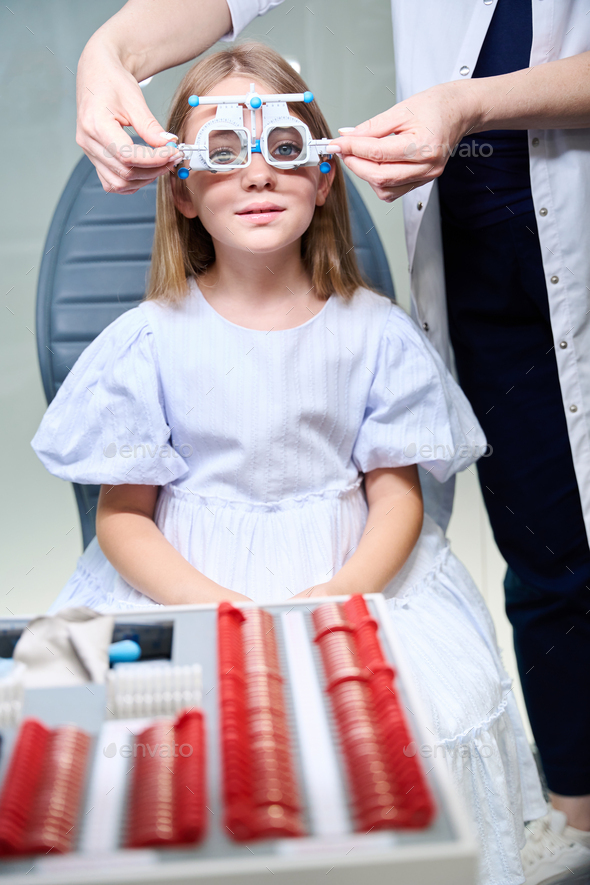 Tranquil little girl taking subjective refraction test in ...