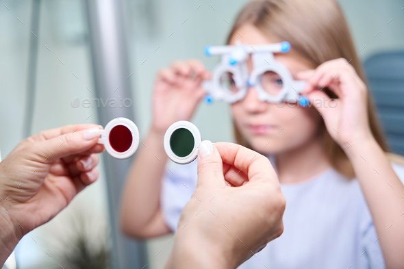 Experienced optometrist conducting duochrome test on little patient ...