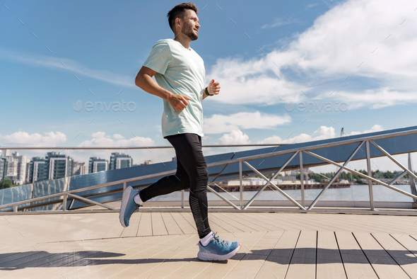 A sporty man running a lot in running shoes. Man running in the city ...
