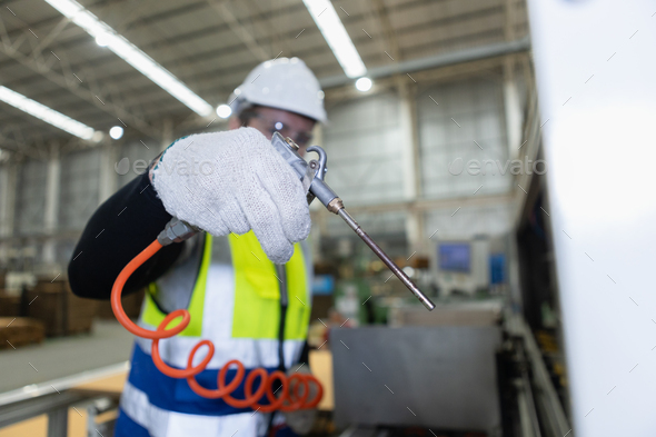 Staff worker man using Compressor Air Blow Gun cleans dust in machine ...