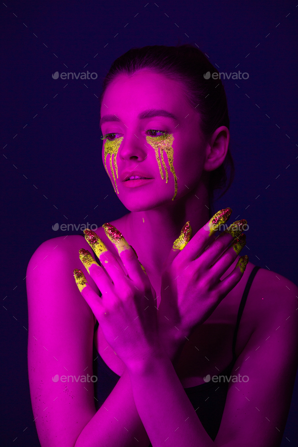 Fashion portrait. A girl with fluorescent paint on her body poses under ...