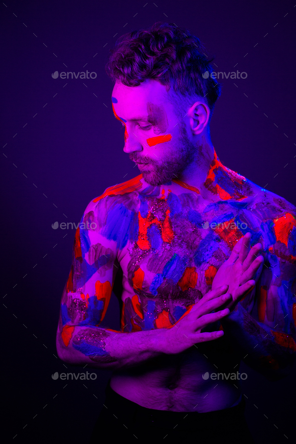 Fashion portrait of a man with ultraviolet paint on his body and neon ...
