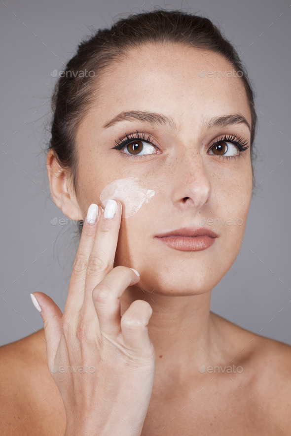 Delighted female with radiant skin applying cream Stock Photo by carlesmiro