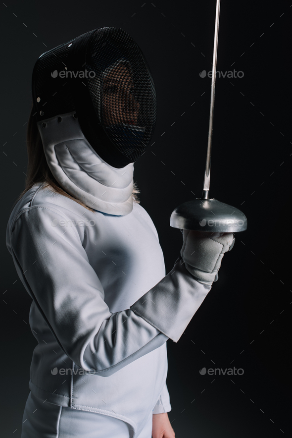 Side view of fencer in fencing mask holing rapier isolated on black ...