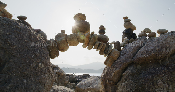 Arch of pebbles in balancing on the sea coast Stock Photo by leungchopan