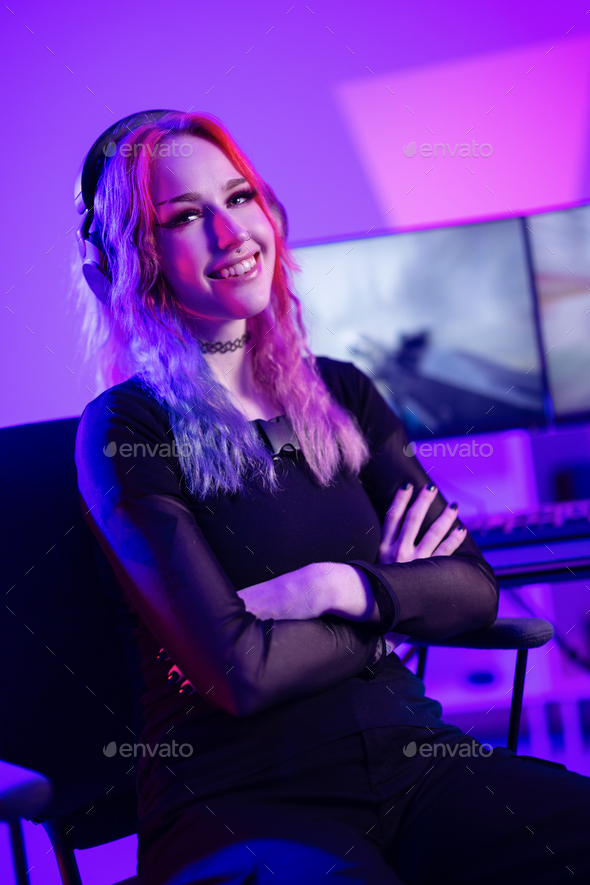 Portrait of a smiling e-sport gamer girl sitting in front of her ...