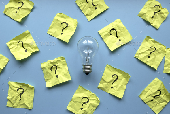 Light bulb with a questions symbol written on a yellow paper over a ...