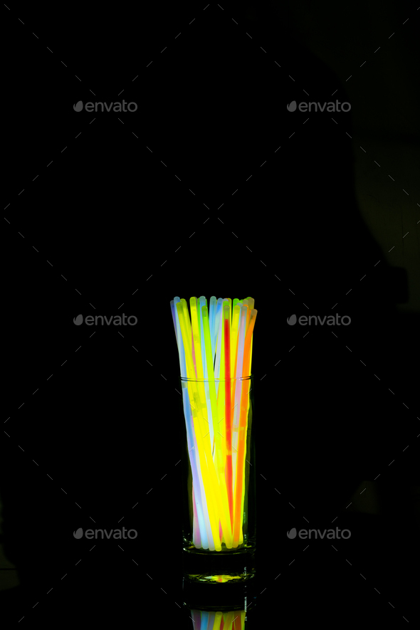 Image of vibrant stack of neon glow sticks in glass over black ...