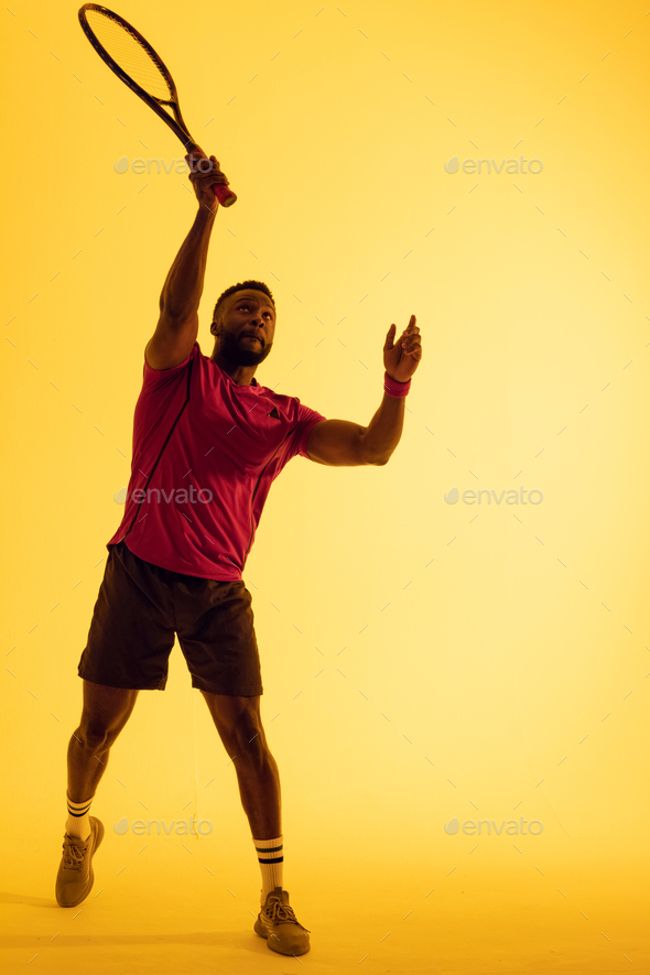 Vertical image of african american male tennis player hitting ball in ...