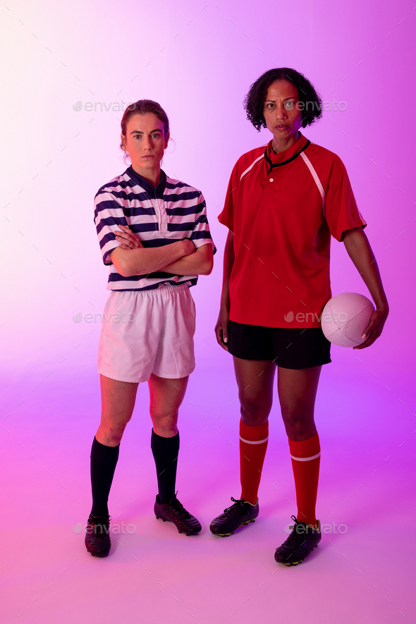 Portrait of two diverse female rugby players with rugby ball over neon ...