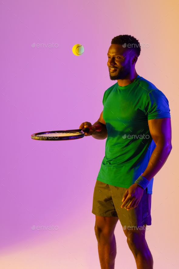Vertical image of happy african american male tennis player in violet ...