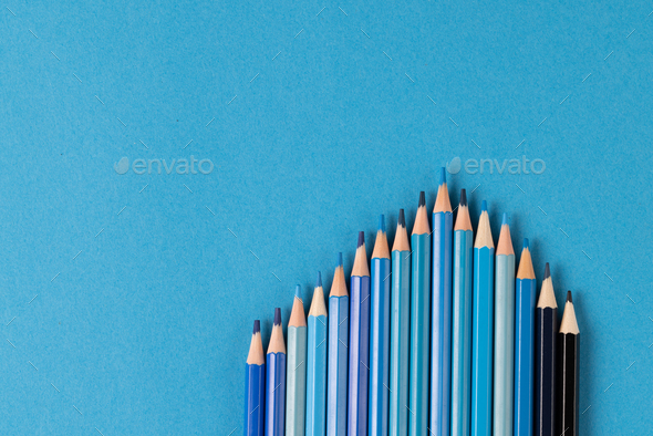 Image of row of different shades of blue crayons on blue background ...