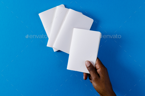Hand of biracial man holding notebook over notebooks with copy space on ...