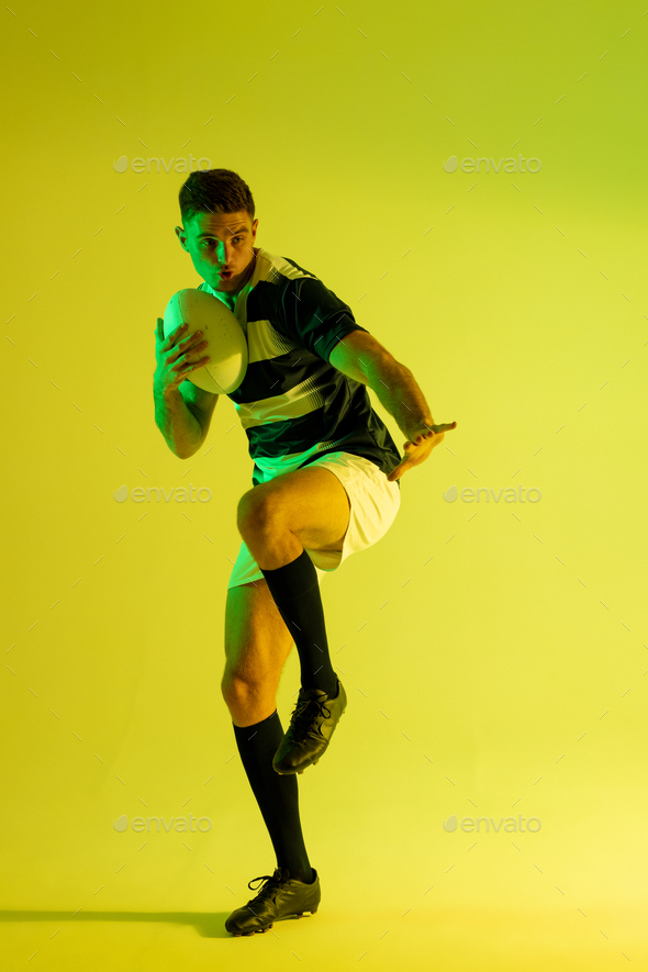 Caucasian male rugby player with rugby ball over yellow lighting Stock ...