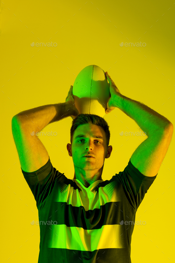Portrait of caucasian male rugby player with rugby ball over yellow ...