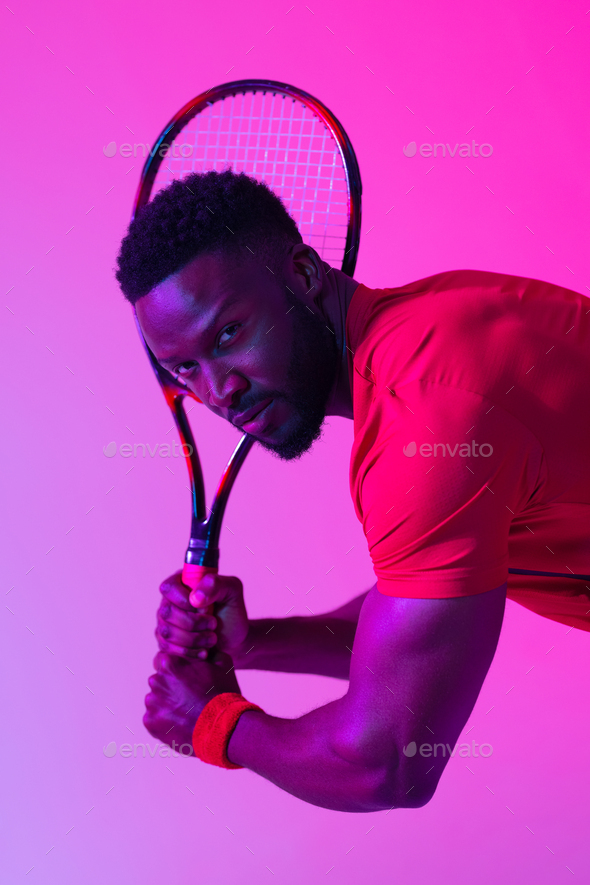 Vertical image of african american male tennis player in neon pink ...
