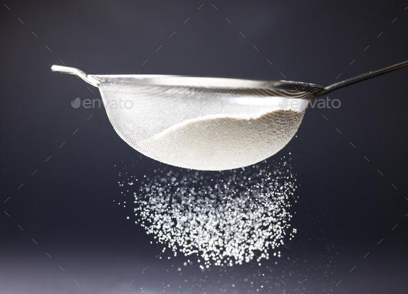 Close-up of flour sifting by sieve against black background, copy space ...