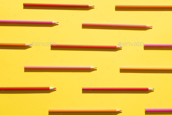 Imagine of crayons of different shades of pink on yellow background ...