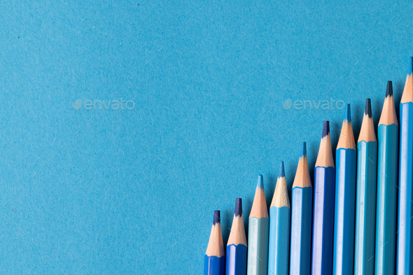 Image of row of different shades of blue crayons on blue background ...