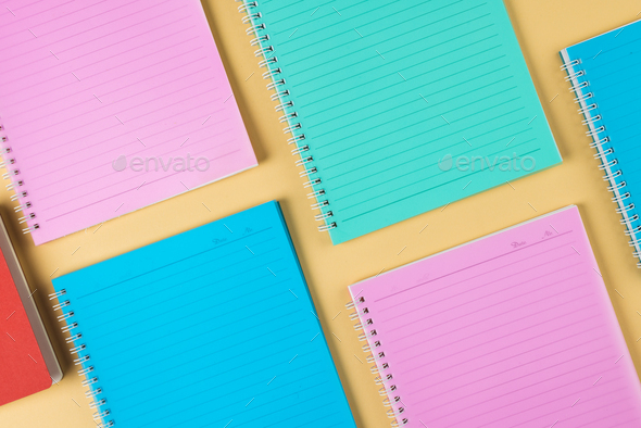 Composition of diverse colorful notebooks lying on yellow surface Stock ...