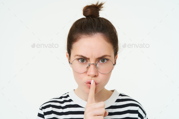 Image of serious woman in glasses, teacher shushing, makes shush, hush ...