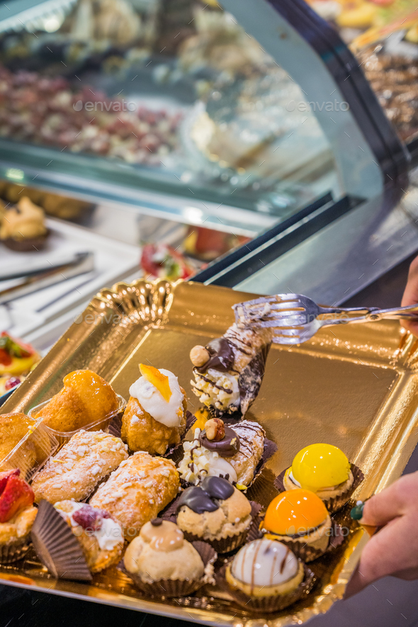 Close up of hands of the pastry man grabbing a tray of pastry to serve ...