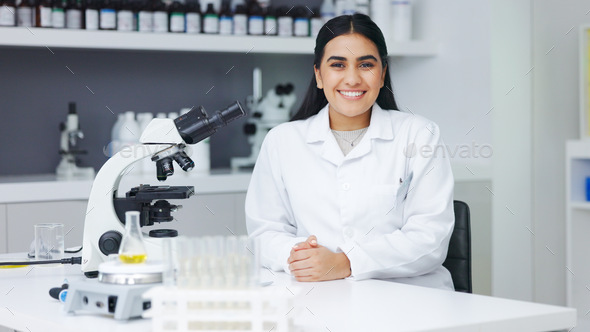 Portrait of a female scientist using a microscope in a research lab ...