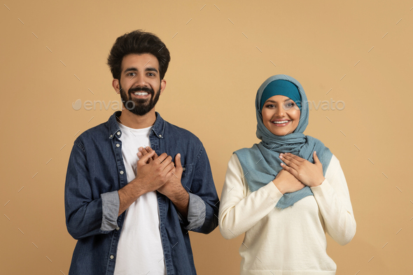 Grateful muslim couple keeping both hands on chest, expressing ...