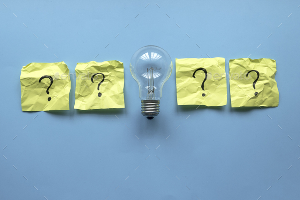 Light bulb with a questions symbol written on a yellow paper over a ...