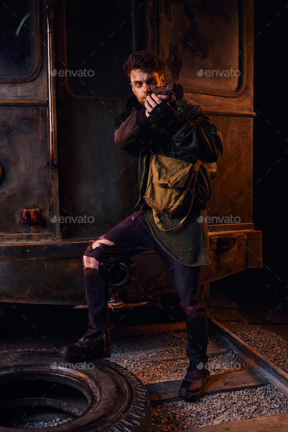 game character in worn outfit aiming with gun in abandoned subway, post ...