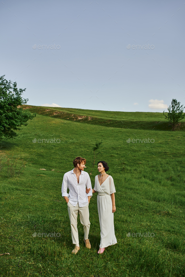 scenic landscape, young newlyweds in wedding gown walking together in ...