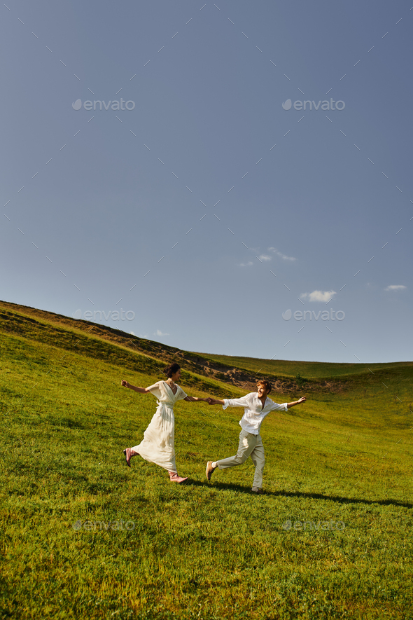 scenic landscape, young newlyweds in wedding gown running in green ...