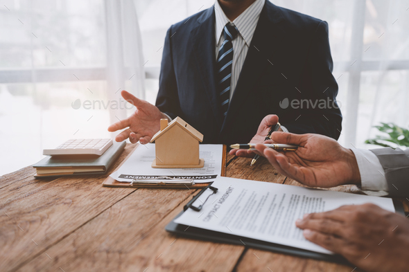 A real estate agent is explaining model house plans and agreeing on a ...