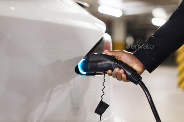 Male hand inserting plug in e-car's port in parking space Stock Photo ...