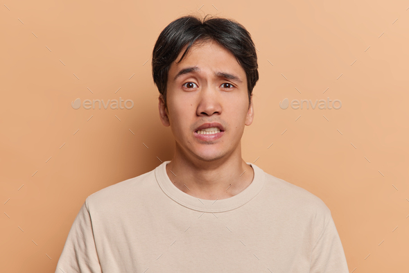 Human facial expressions concept. Brunet young Japanese man clenches ...