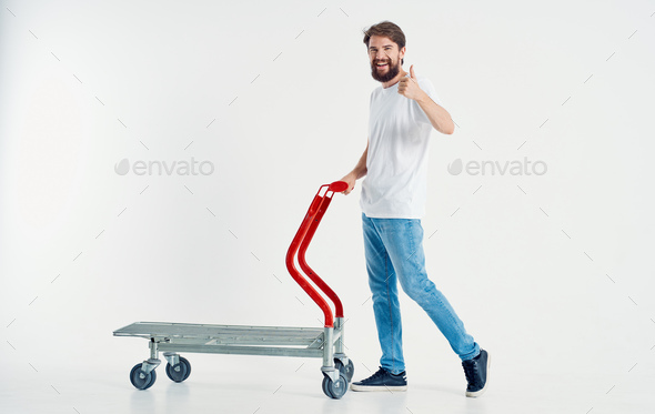 cargo trolley man in jeans and sneakers light background work ...