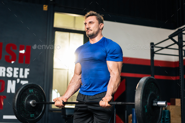 Caucasian sportsman slowly lift up weight machine barbell in stadium ...