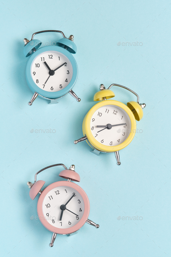 Three alarm clocks of different colors show different times. Start of ...