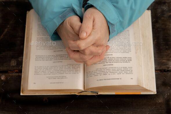 woman with her hands on top of a holy book Stock Photo by wirestock