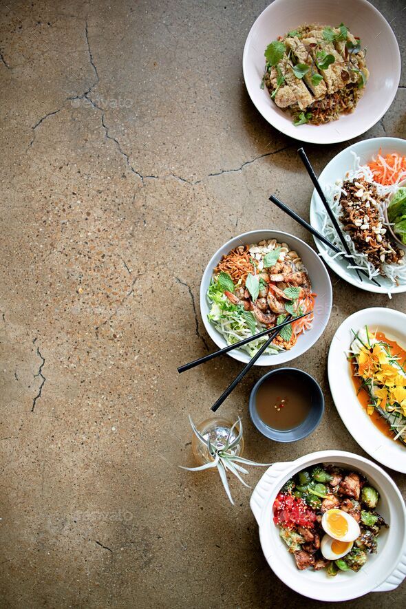 Vertical top view of bowls of gourmet Asian dishes on a brown table ...