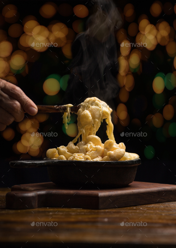 Close-up vertical shot of a hand pouring hot cheesy cobetti rigati ...