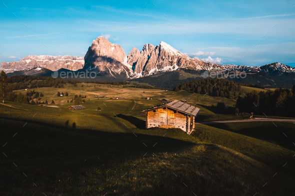 Aerial view of a rural house on wide grassland and snow rocky cliffs in ...
