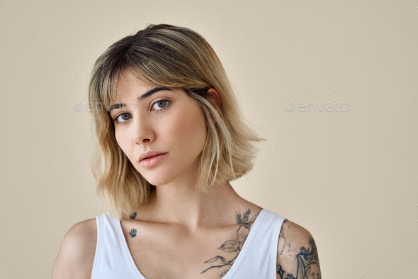 Cool blonde gen z girl pretty face and tattoos at beige background ...