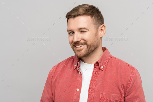 Handsome flirty smiling man winking to camera isolated on studio ...